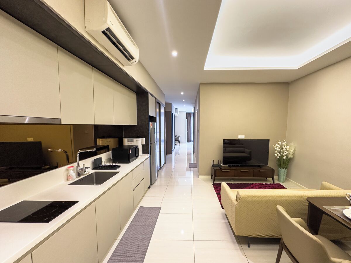 Uma cozinha moderna com uma ilha central, uma sala de jantar com televisão e uma sala de estar com sofá e mesa de centro.