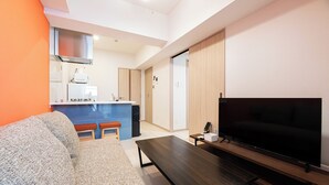 Uma sala de estar moderna com televisão de tela plana, um sofá e uma mesa de centro.