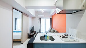 Quarto de hotel com cozinha compacta, uma cama, TV e vista para a cidade.