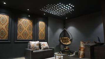 Uma sala de estar moderna com um sofá cinza escuro, painéis de parede estampados, uma cadeira suspensa e uma mesa de centro redonda.