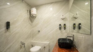 Um banheiro moderno com parede de mármore, pia preta, vaso sanitário e chuveiro manual.