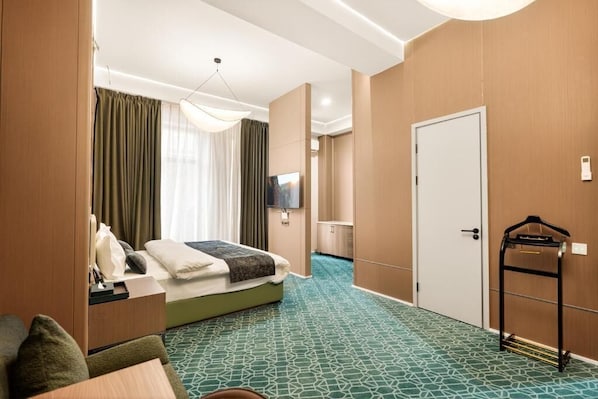Quarto de hotel com cama, televisão, guarda-roupa e banheiro.