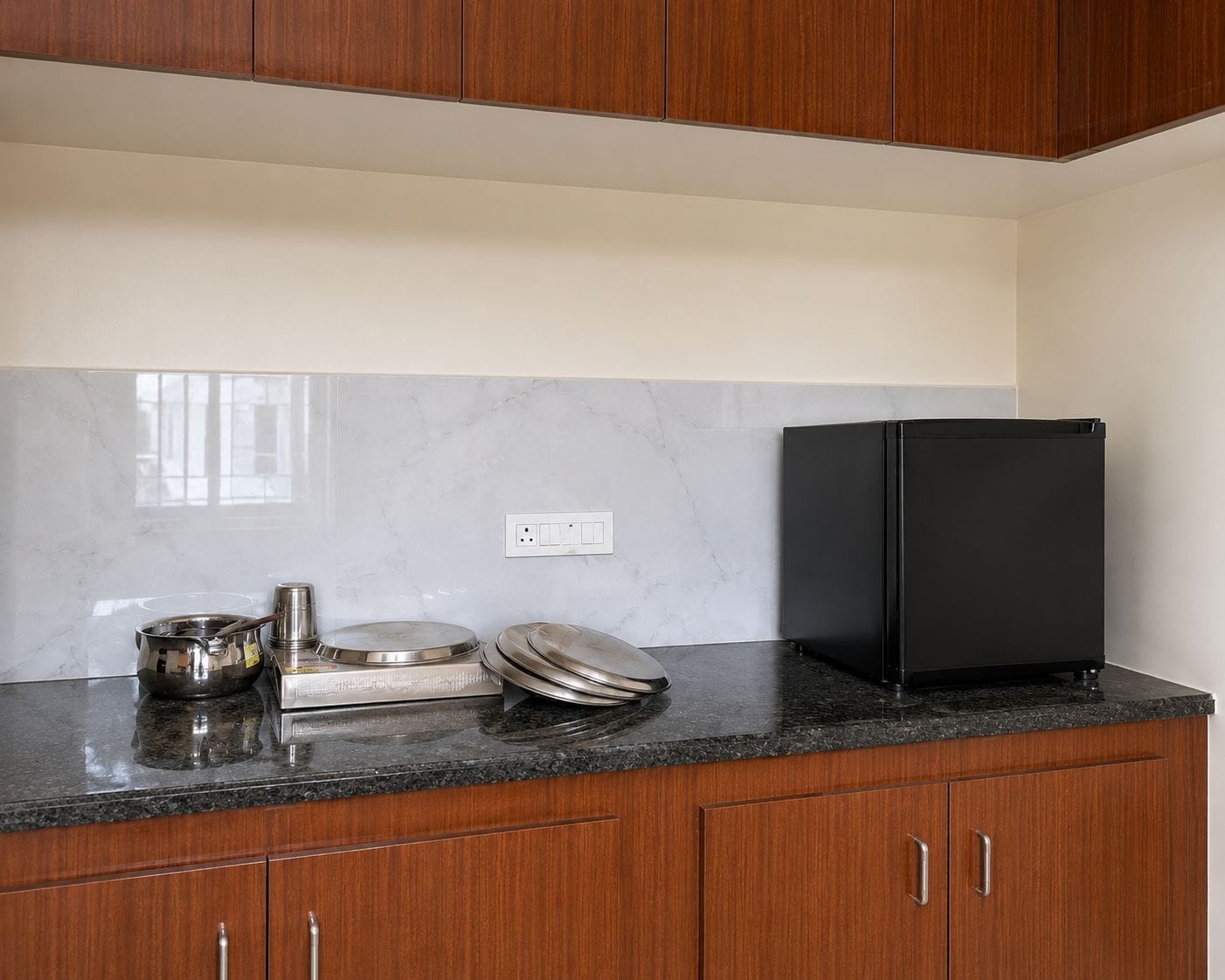 Cozinha com backsplash de mármore, geladeira preta e armários de madeira.
