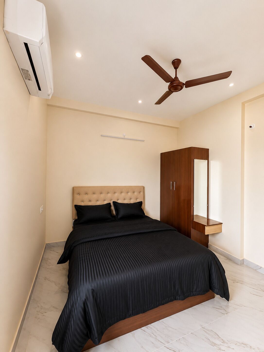 Quarto com cama, ventilador de teto, guarda-roupa e ar condicionado.