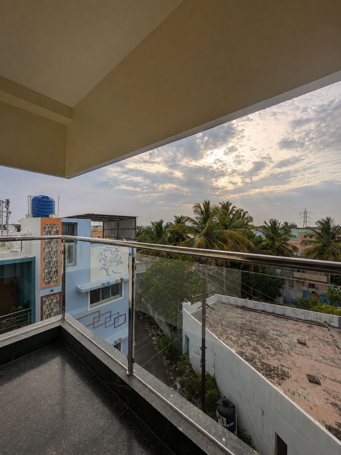 Varanda com vista para uma área residencial, incluindo edifícios e palmeiras.