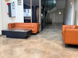 Um hall moderno com um sofá de couro, uma mesa de centro de mármore e uma escada que leva a um andar superior.