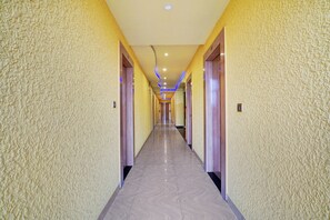 Um corredor comprido e estreito com parede texturizada e chão polido, que leva a uma porta no final.