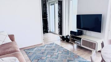 Uma sala de estar moderna com uma televisão de tela plana, uma mesa de centro, um sofá e um tapete estampado.