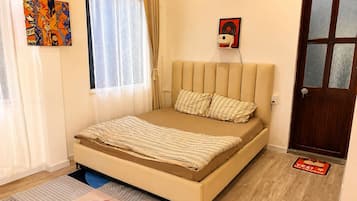 Quarto com cama, cortinas, uma porta e um quadro pendurado na parede.