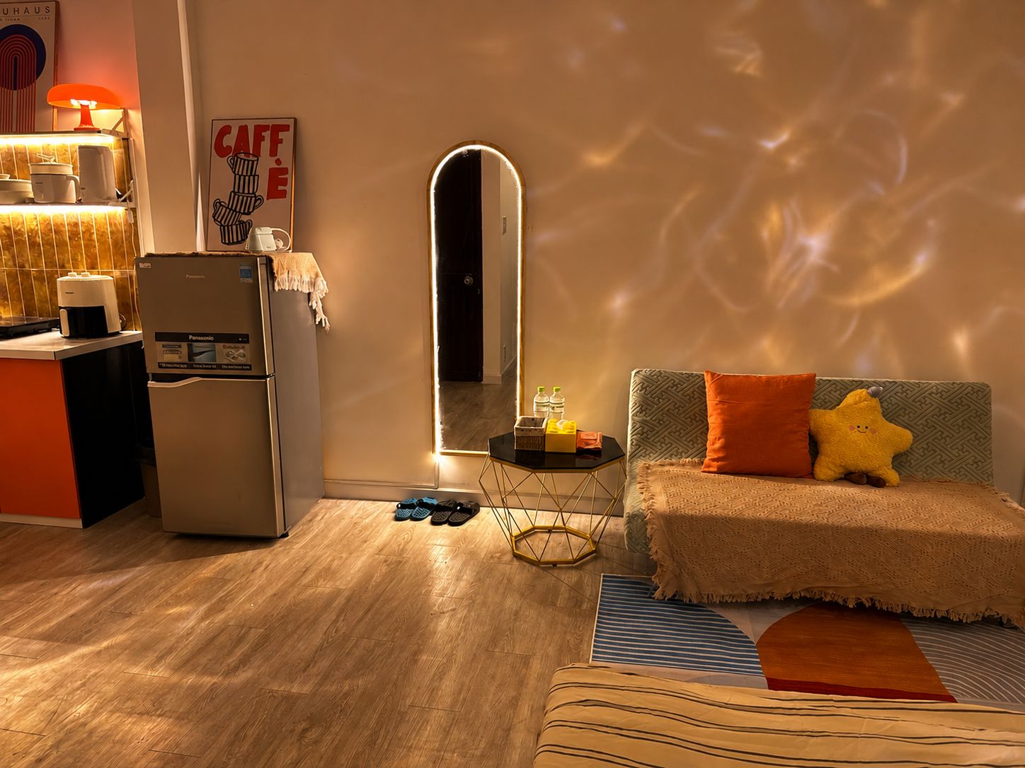 Uma sala de estar moderna com cozinha, um espelho grande e um sofá confortável com almofadas decorativas.