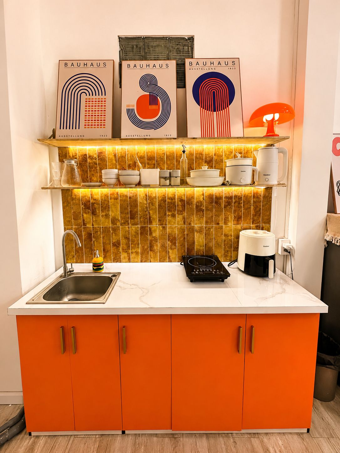Cozinha com bancada branca, armários laranja e painel de fundo com padrões geométricos.