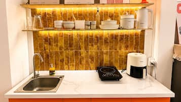 Cozinha com bancada branca, armários laranja e painel de fundo com padrões geométricos.