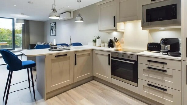 Uma cozinha moderna com uma ilha central, forno embutido e eletrodomésticos de aço inoxidável.