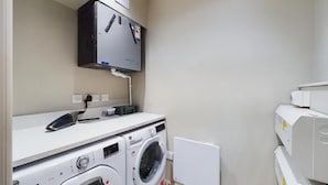 A laundry room with a washing machine, dryer, and a wall-mounted television.
