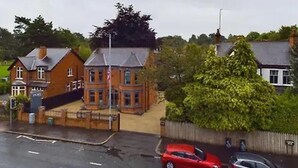 A residential area with houses, a flag, and parked cars.