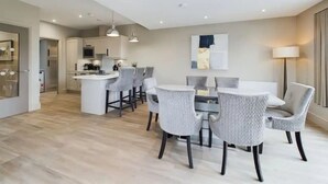 A modern kitchen with white cabinetry, a central island, and a dining area with a round table and chairs.