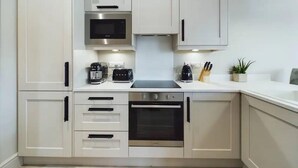 A modern kitchen with stainless steel appliances, white cabinetry, and a central island.