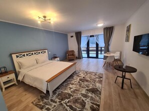 Quarto com cama, mesa de cabeceira e vista para uma varanda.