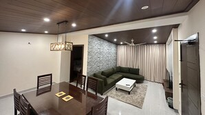 Um espaço moderno com área de jantar, sofá verde e mesa de centro branca.