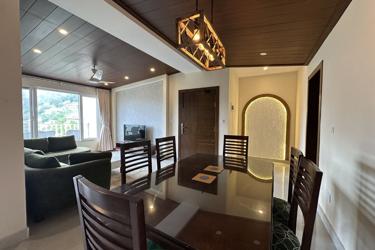Uma sala de jantar moderna com uma mesa de vidro, cadeiras de madeira e uma luminária geométrica original.
