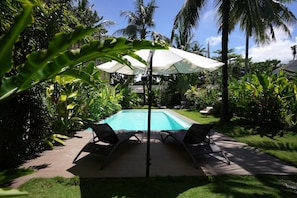 Uma piscina com duas espreguiçadeiras e um grande guarda-sol.
