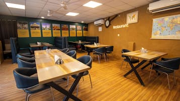 Um restaurante com cabines e mesas, um mapa-múndi na parede e um relógio.