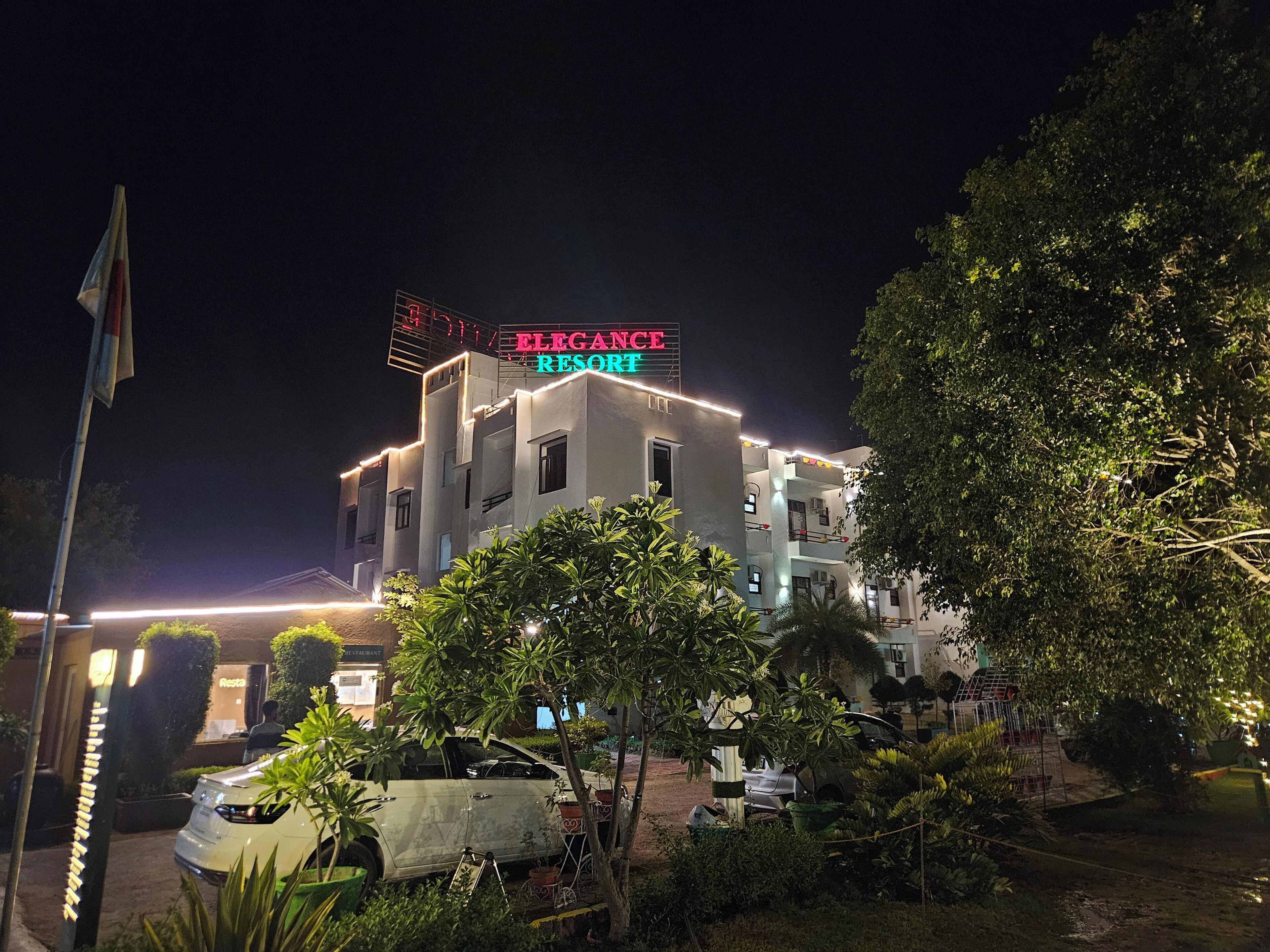 Um edifício com uma placa que diz 'ELEGANCE RESORT' à noite.