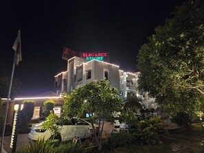 Um edifício com uma placa que diz 'ELEGANCE RESORT' à noite.