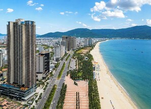 Paisagem costeira com edifícios altos, uma praia e céu claro.