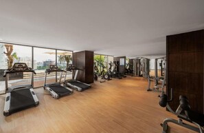 Uma academia com esteiras, bicicletas ergométricas e aparelhos de musculação.