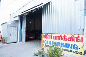 Carro estacionado em um edifício com placa indicando serviços de estacionamento.
