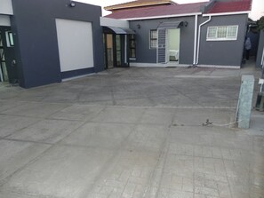 Edifício residencial com porta de garagem, pequena entrada e calçada pavimentada.