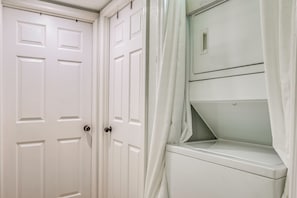 Uma porta branca com puxador e um armário branco com prateleira.