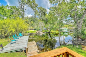 Um deck de madeira com cadeiras, um lago e uma casa pequena com telhado amarelo.