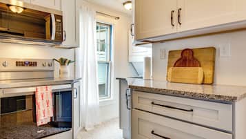 Uma cozinha moderna com eletrodomésticos de aço inoxidável, tábua de corte de madeira e uma janela com cortinas.