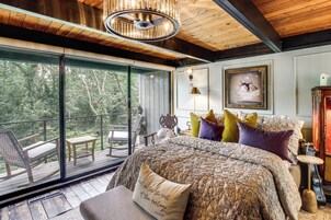 Quarto com uma cama grande, vista para o exterior e varanda com mobiliário.