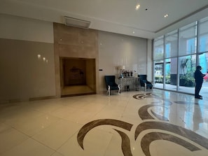 Um hall amplo com piso de azulejos, um balcão de recepção e uma grande janela com vista para o exterior.