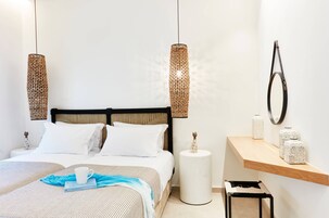 Quarto moderno com cama, mesas de cabeceira, abajur e um pequeno banquinho.