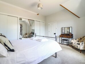 Quarto com cama, cadeira, penteadeira, espelho e guarda-roupa.