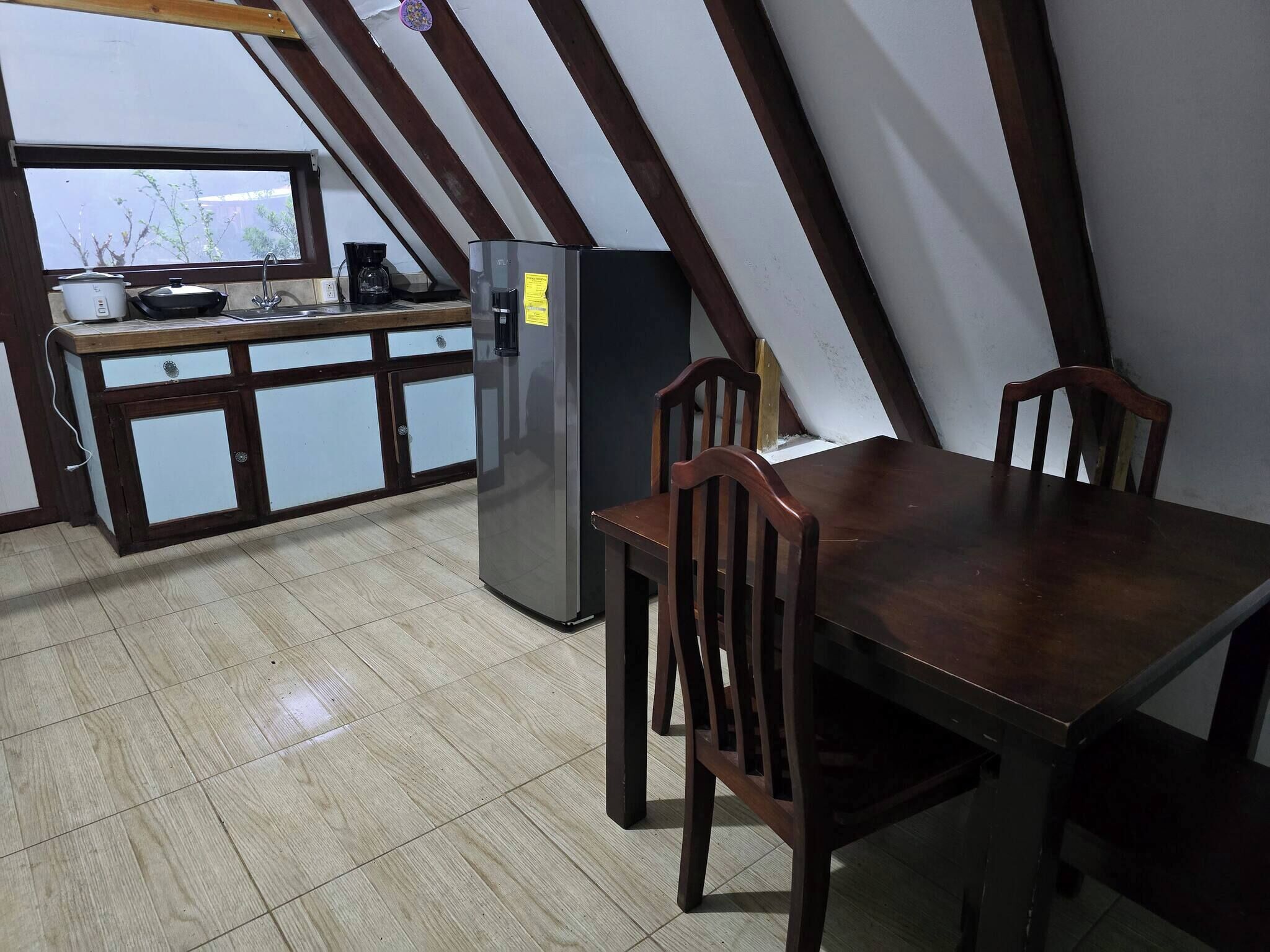 A kitchen with a dining table and chairs, a refrigerator, and a window.