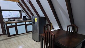 Uma cozinha com mesa e cadeiras, geladeira e janela.