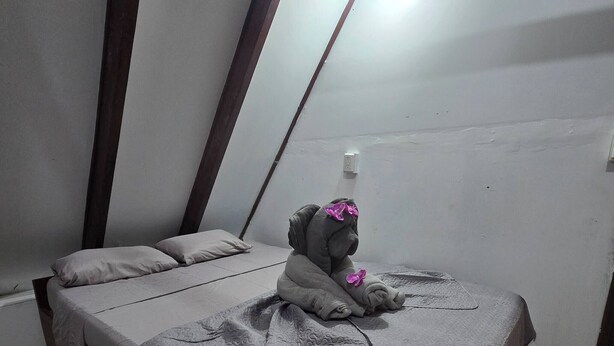 Quarto com cama, uma mesinha e uma tomada.