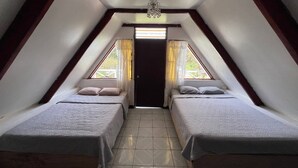 Um quarto de sótão pequeno com duas camas, teto inclinado e janela com cortinas.