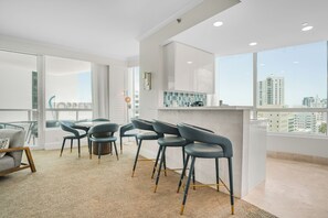 Interior moderno com área de jantar, cozinha e grandes janelas com vista para a cidade.