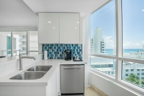 Uma cozinha moderna com uma pia de aço inoxidável, uma máquina de lavar louça e uma cafeteira sobre a bancada.