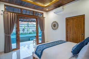 Quarto com cama, porta de madeira e vista para uma piscina.