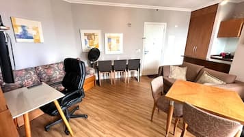 Uma sala de estar com sofá, mesa de jantar, mesinha de centro e televisão.