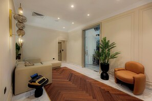Uma sala de estar moderna com um sofá, uma poltrona, uma mesa de centro e um vaso de planta.
