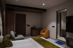 Quarto de hotel com cama, escrivaninha, cadeira, televisão e guarda-roupa.