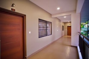 Corredor com porta de madeira identificada com o número '102', janela com grades de metal e varanda com corrimão.